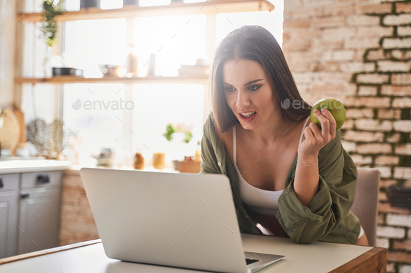 Attentive brunette girl staring at screen of her laptop Stock Photo by ...