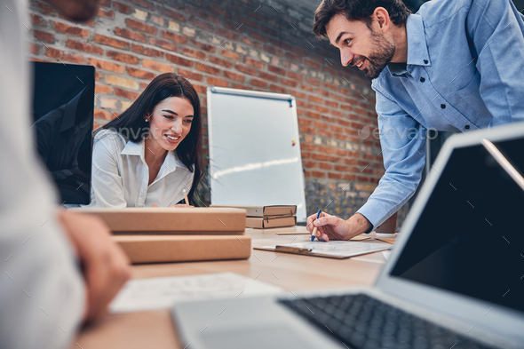 Happy coworkers writing notes while working together Stock Photo by ...