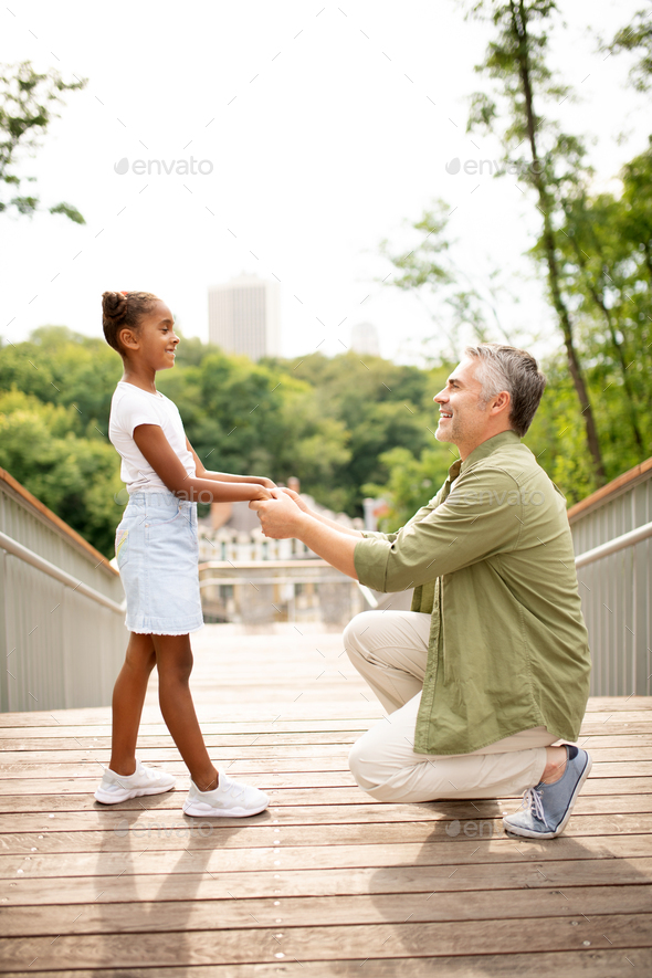 Loving father standing on his knee while talking to his daughter Stock ...