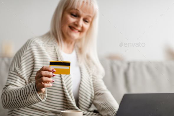 Smiling mature woman using credit card at home Stock Photo by Prostock ...