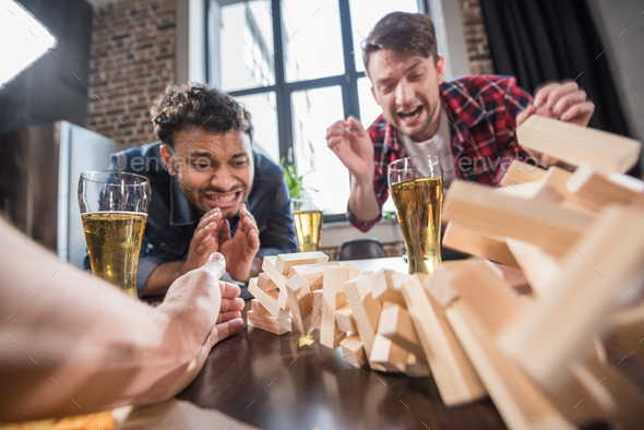 young men playing jenga game, jenga blocks falling. young people having ...