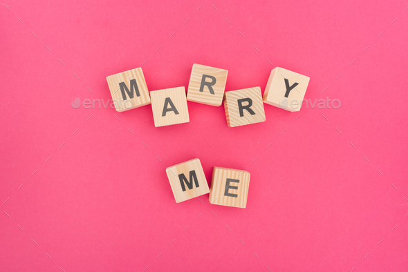 top view of marry me lettering made of wooden blocks on pink background ...