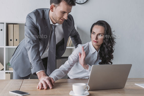 angry secretary showing stop gesture to businessman touching her hand ...