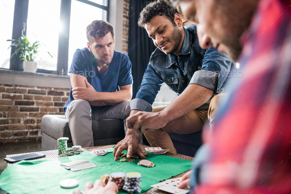 Young men playing cards at gaming table, young people having fun ...