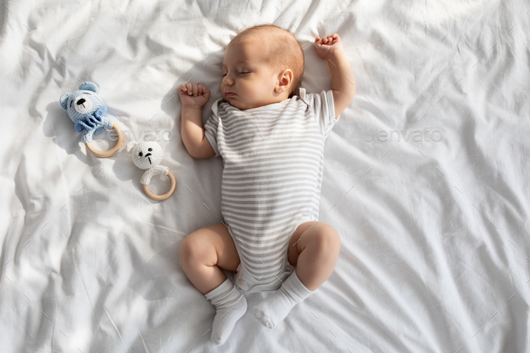 Portrait Of Adorable Newborn Child Napping On Bed With Rattle Toys ...