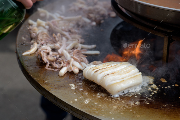 Octopus meat is prepared at the street food festival with smoke and ...