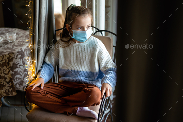 Sad child girl wearing protective mask at home. People coronavirus ...