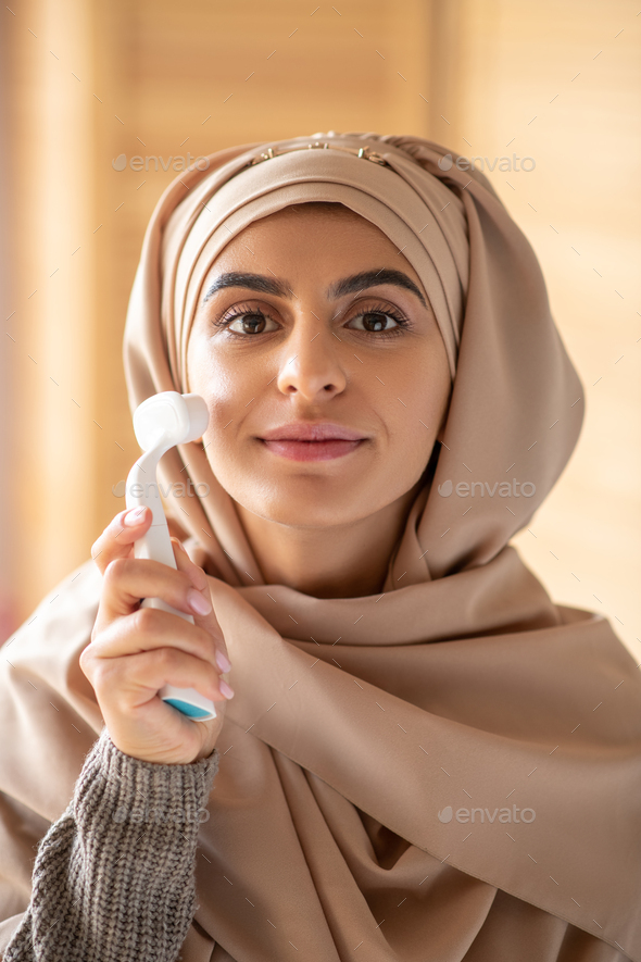 Beautiful Muslim girl using facial cleansing brush Stock Photo by ...