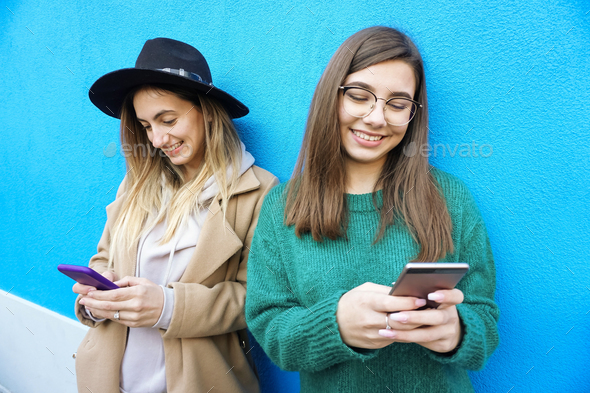 Teenagers using smartphones and being smiling while using technology ...