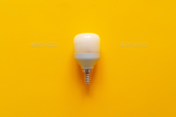 Light bulb on yellow paper background top view Stock Photo by FabrikaPhoto
