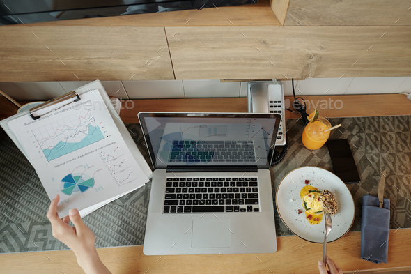 Businesswoman Eating and Working with Documents Stock Photo by DragonImages