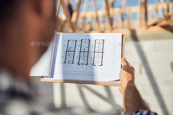 Experienced field engineer looking at schematic plan of a building ...