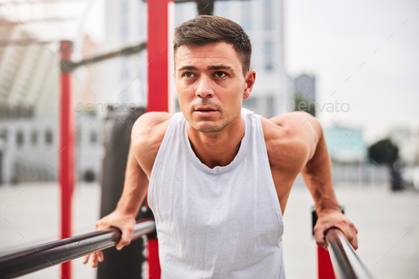 Muscular man training with self weight outdoors Stock Photo by svitlanah