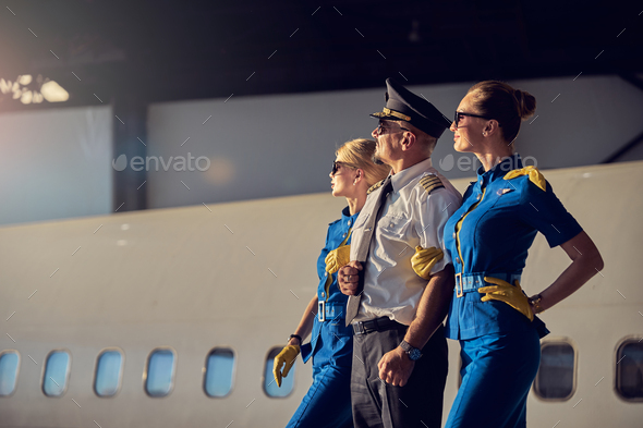Elegant charming women flight stewardesses with captain of aircraft ...