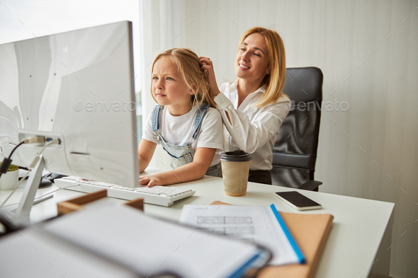 Female child playing on the computer her mom in the office place Stock ...