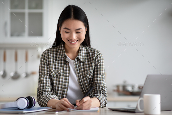Positive asian woman taking notes while attending online class Stock ...