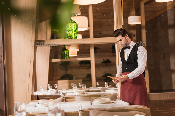 Waiter standing and looking at menu at the restaurant Stock Photo by ...