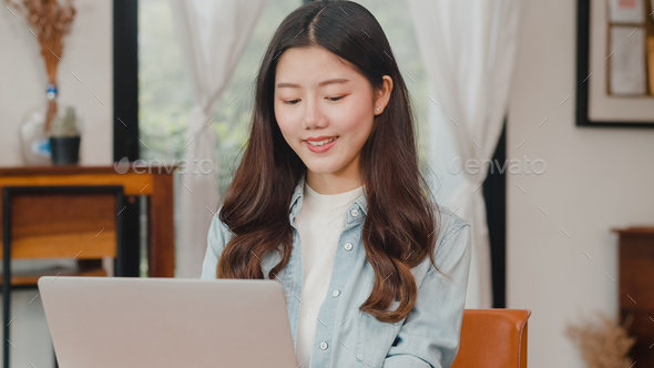 Cheerful Young Asian freelance lady working on laptop at coffee shop ...