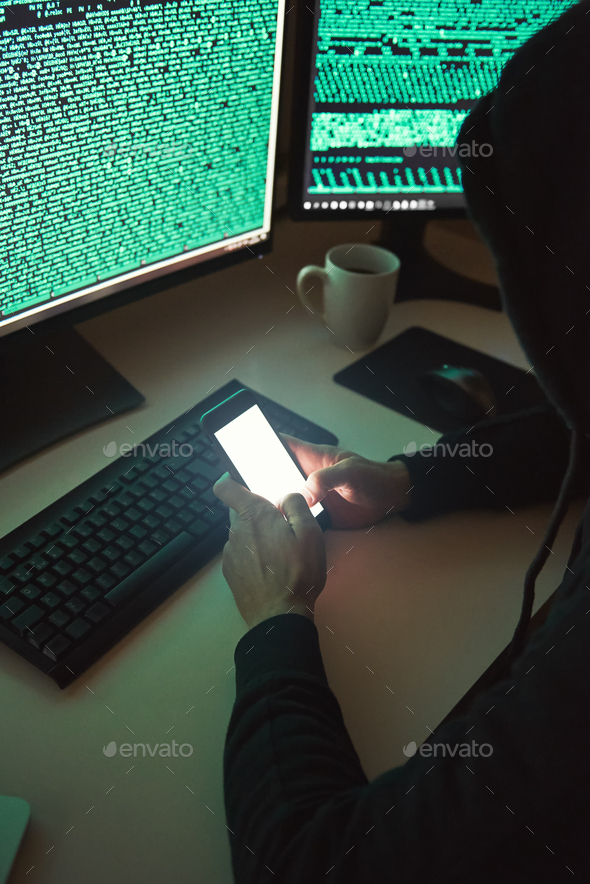 Vertical photo of young hacker in black hoodie using multiple computers ...