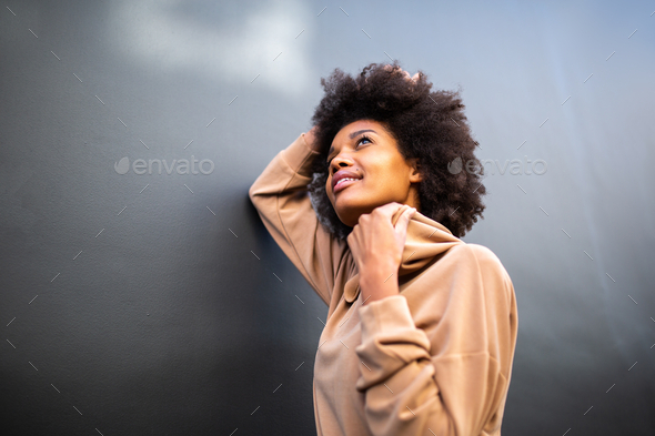 beautiful young African american woman leaning against gray wall Stock ...
