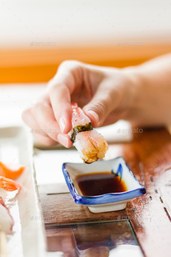 Hand girl dipping a piece of sushi on soya sauce Stock Photo by ...