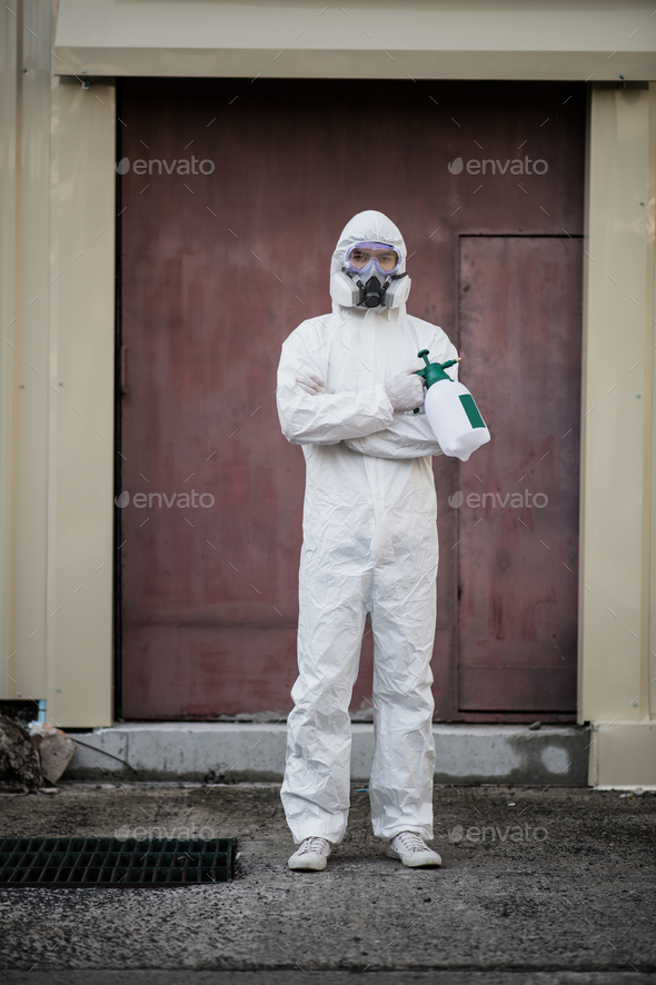 Disinfection specialist in PPE suit performing public decontamination ...