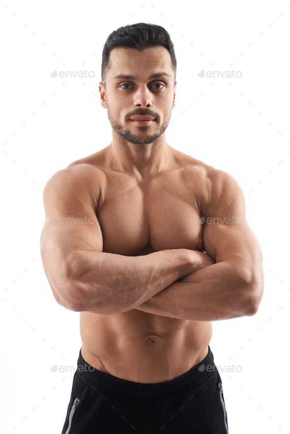 Shirtless bodybuilder posing with crossed arms Stock Photo by serhiibobyk