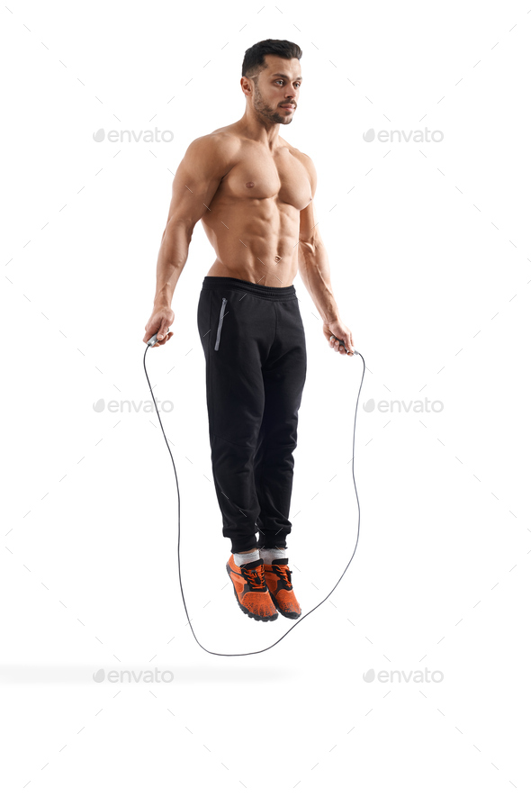 Shirtless bodybuilder jumping using rope Stock Photo by serhiibobyk