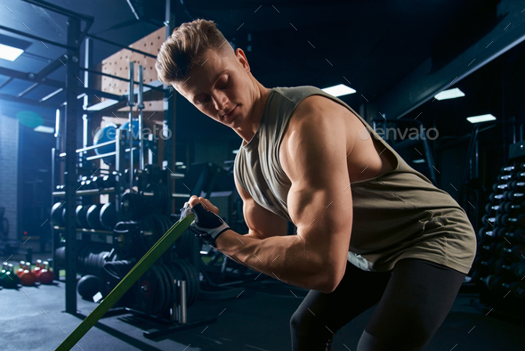 Bodybuilder training arm with resistance band Stock Photo by serhiibobyk
