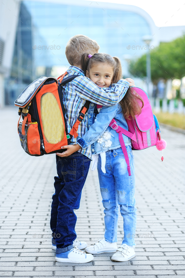Classmates hug near the school. The concept is back to school, study ...