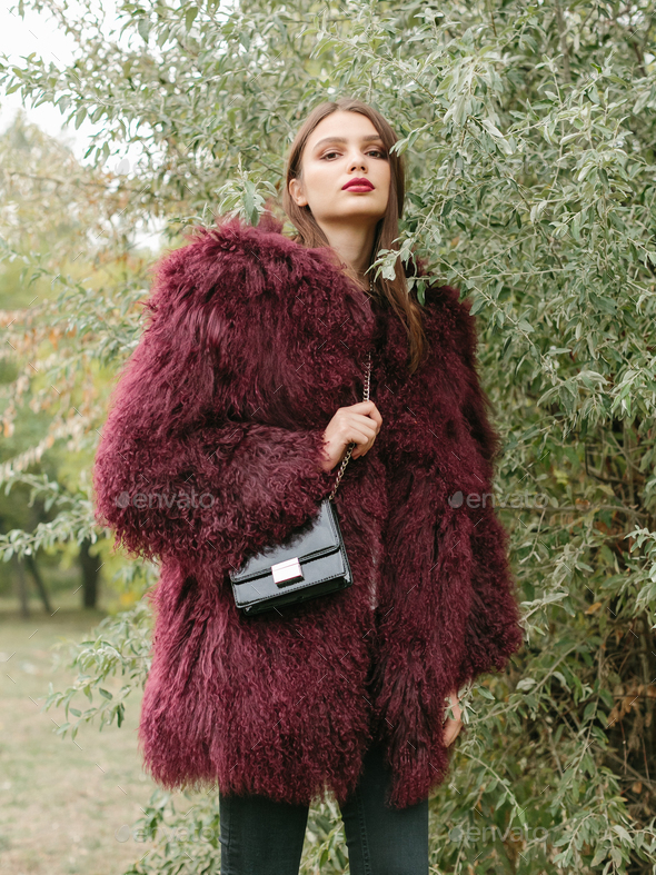 Female with brunette hair and makeup posing in marsala lama fur coat at ...