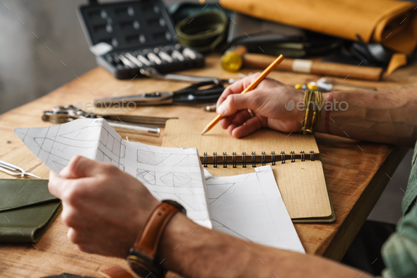 White craftsman drawing while working with leather in workshop Stock ...