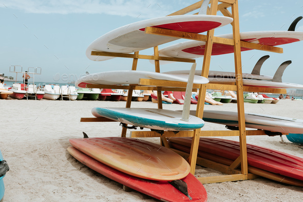 Surfboards stacked on the rack on a beach Stock Photo by FabrikaPhoto