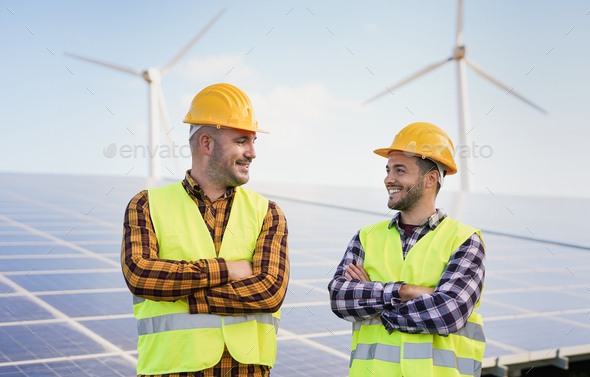 Worker men at solar power station - Solar panels with wind turbines in ...
