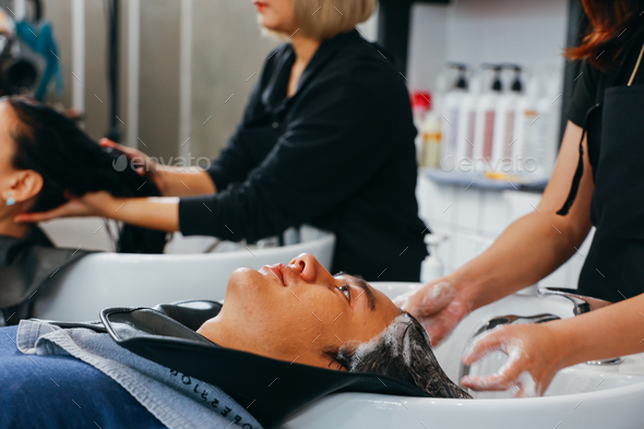 Hairdresser shampooing hair of female customer Stock Photo by twinsterphoto