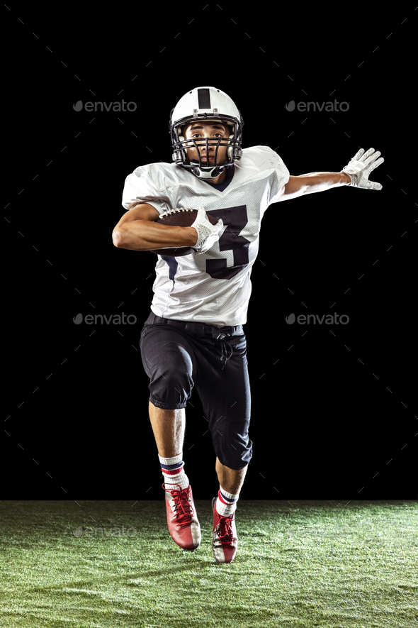 Portrait of American football player training isolated on dark studio ...