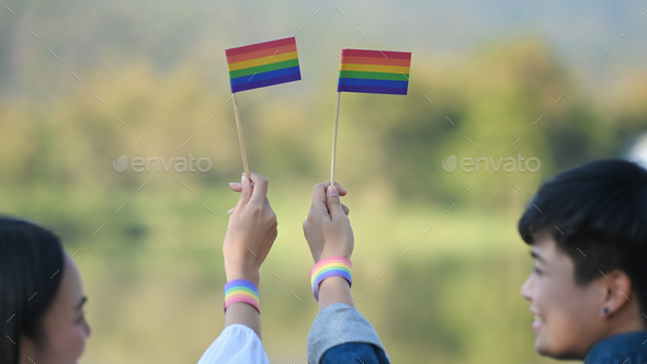 Cropped shot of young LGBT lesbian couple showing a rainbow flag. Stock ...