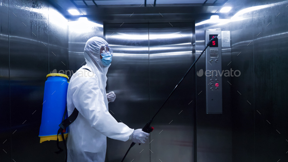 Worker in personal protective equipment (ppe) suit cleaning in building ...