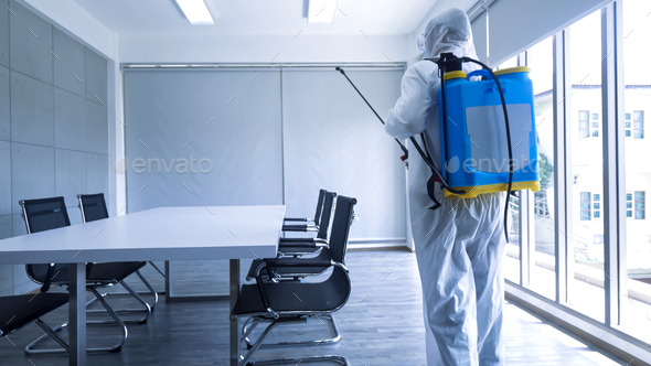 Worker in personal protective equipment (ppe) suit cleaning in building ...