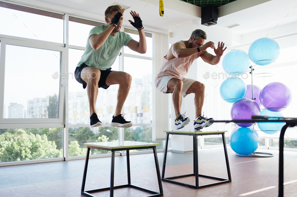 Crossfit box jump exercise. Athletes jumping onto the box at the gym ...
