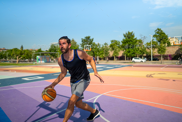 A male basketball player runs on a basketball court with a ball Stock ...