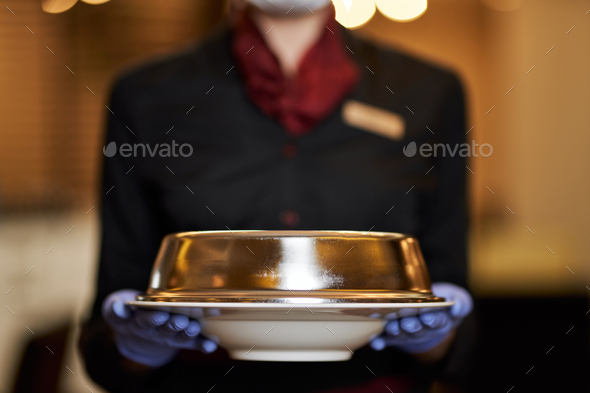 Selective focus photo of covered plate in hands of waitress Stock Photo ...