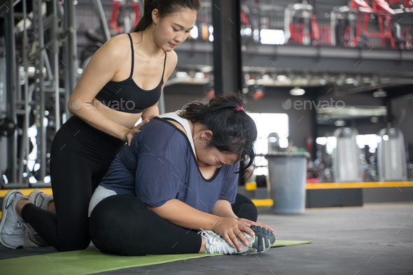 Obese woman and her personal trainer doing exercises at fitness. Stock ...