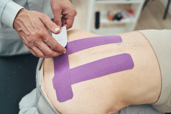 Experienced physiatrist using kinesiology taping method for low back ...