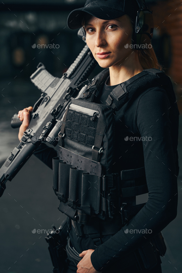 Young female shooter with an assault rifle staring ahead Stock Photo by ...