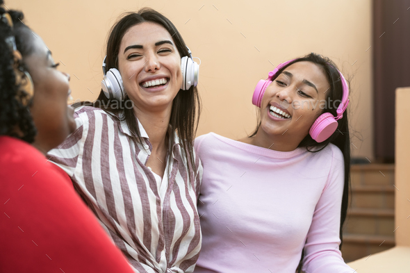 Happy multiracial friends having fun listening music with wireless ...