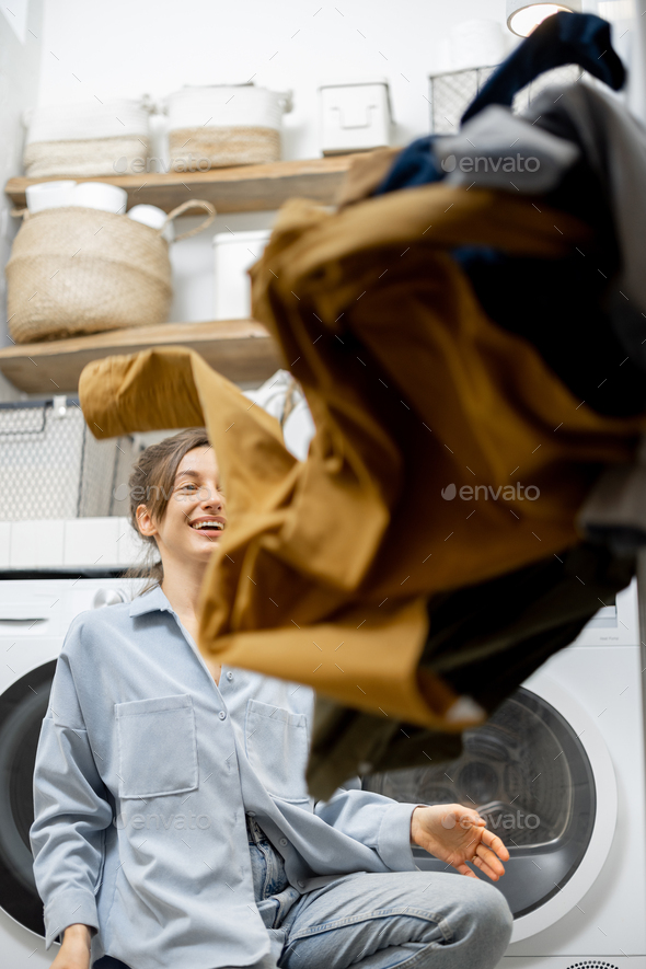 Housewife throwing up clothes at the laundry Stock Photo by RossHelen