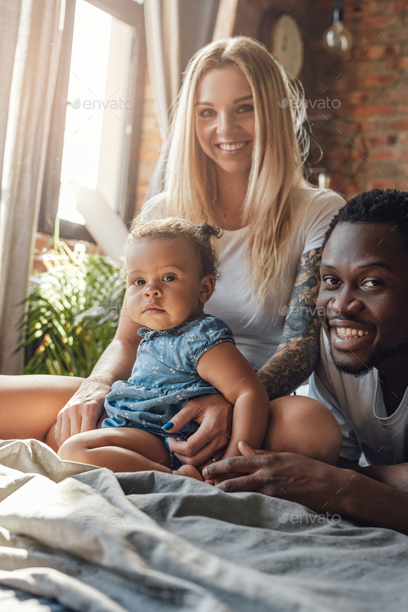 Joyful mixed race couple and their daughter in bedroom Stock Photo by ...