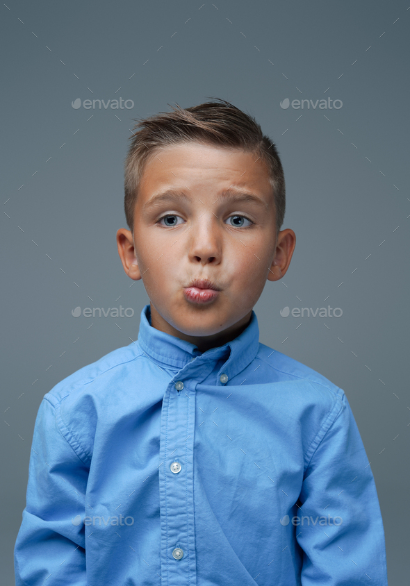Playful boy making face and posing against grey background Stock Photo ...