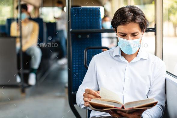 Focused man in mask reading book sitting at autobus Stock Photo by ...